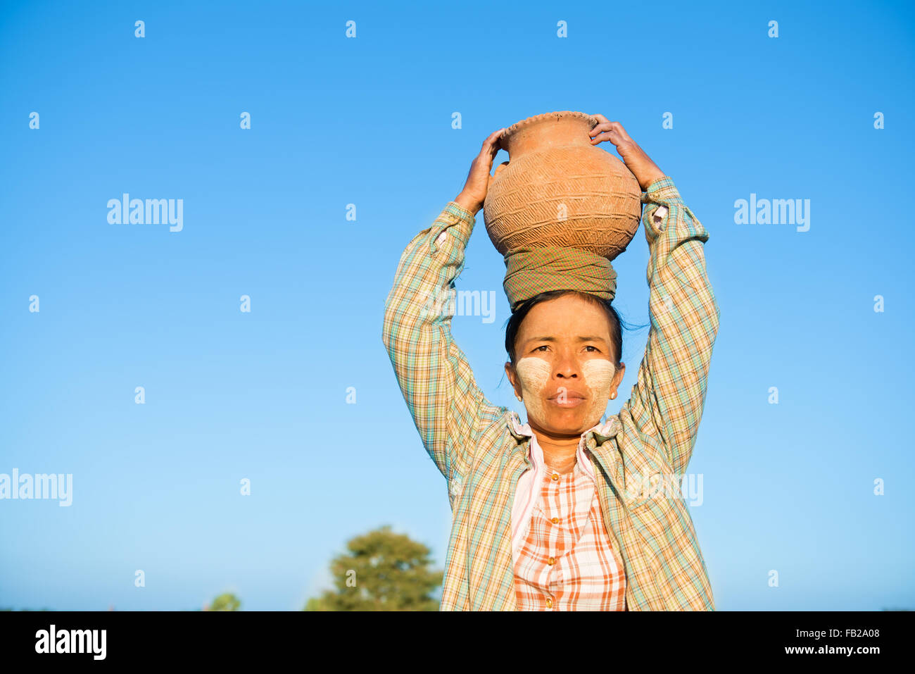 Portrait of mature Asian Burmese traditional female farmer carrying ...