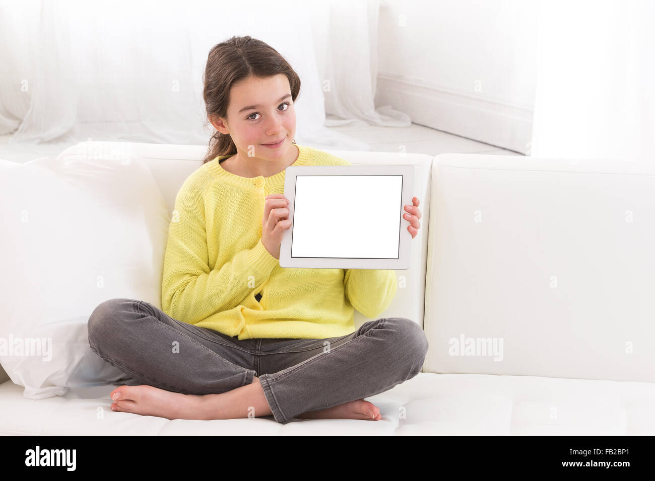 Little girl using digital tablet on sofa at home Stock Photo - Alamy