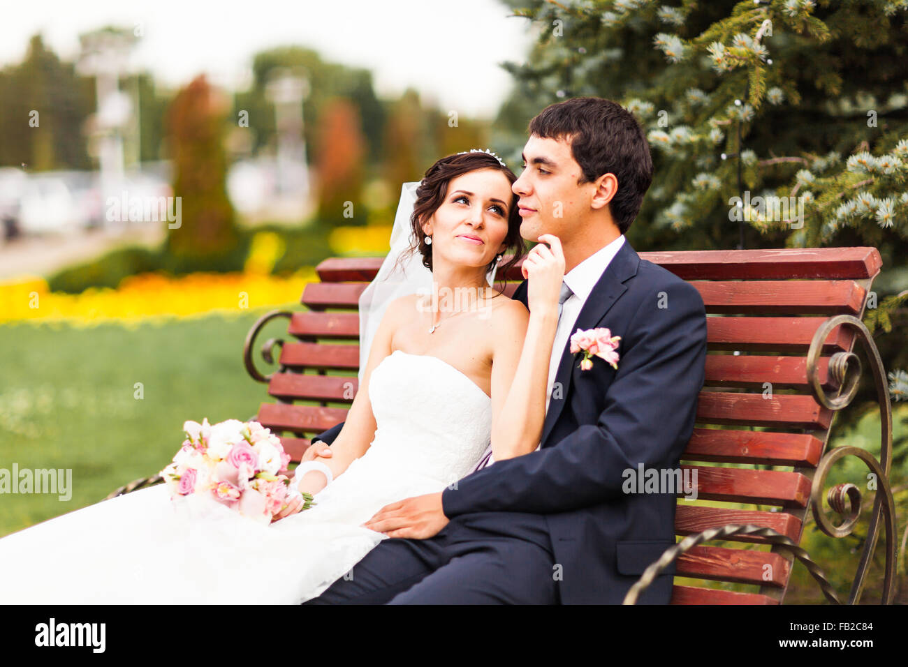 The bride and groom sitting on a bench in the Park Stock Photo - Alamy