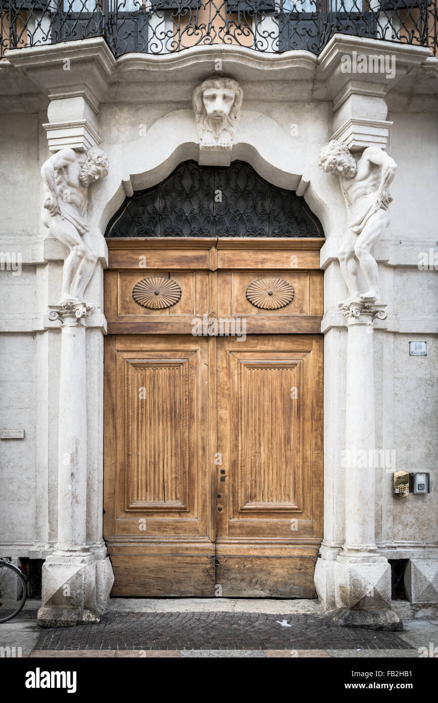 Old white stone entrance and wooden portal with statues that support ...