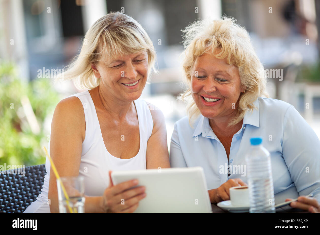 Happy senior women enjoying the time in outdoor cafe. Smiling friends ...