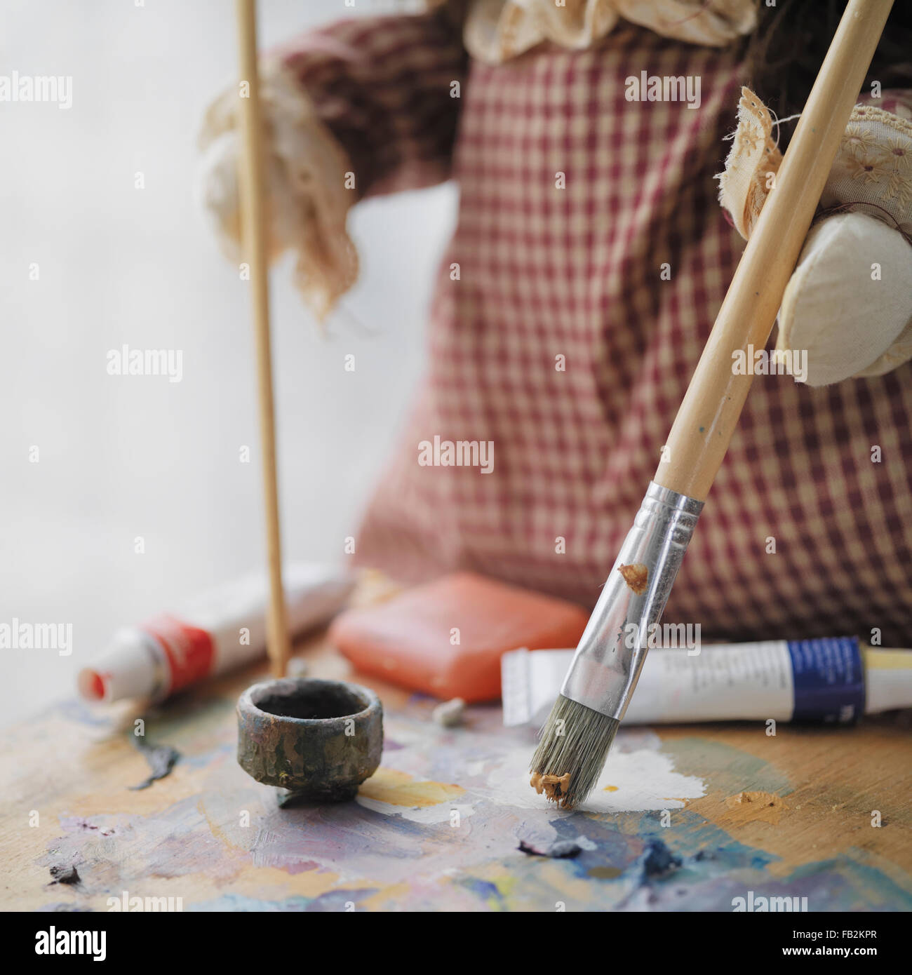 Closeup of a doll painting with artist brushes, selective focus indoor ...