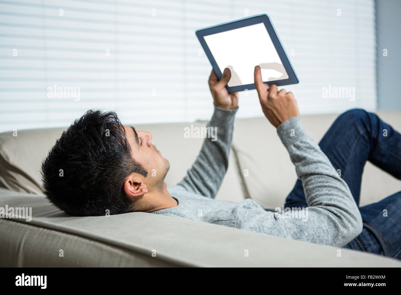 Handsome man using tablet on the sofa Stock Photo - Alamy