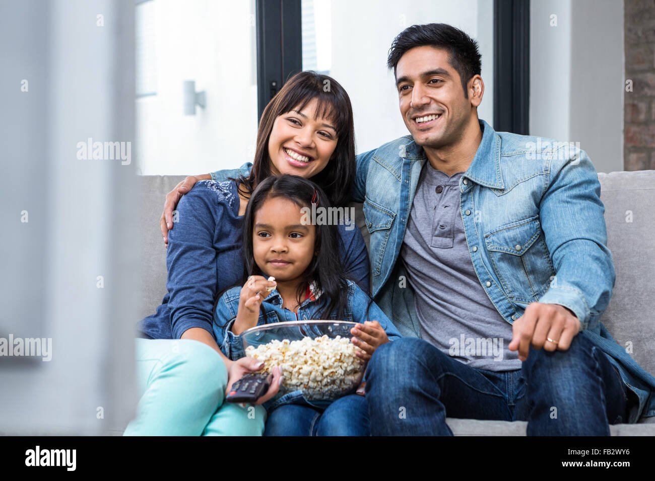 Smiling family eating popcorn while watching tv Stock Photo - Alamy