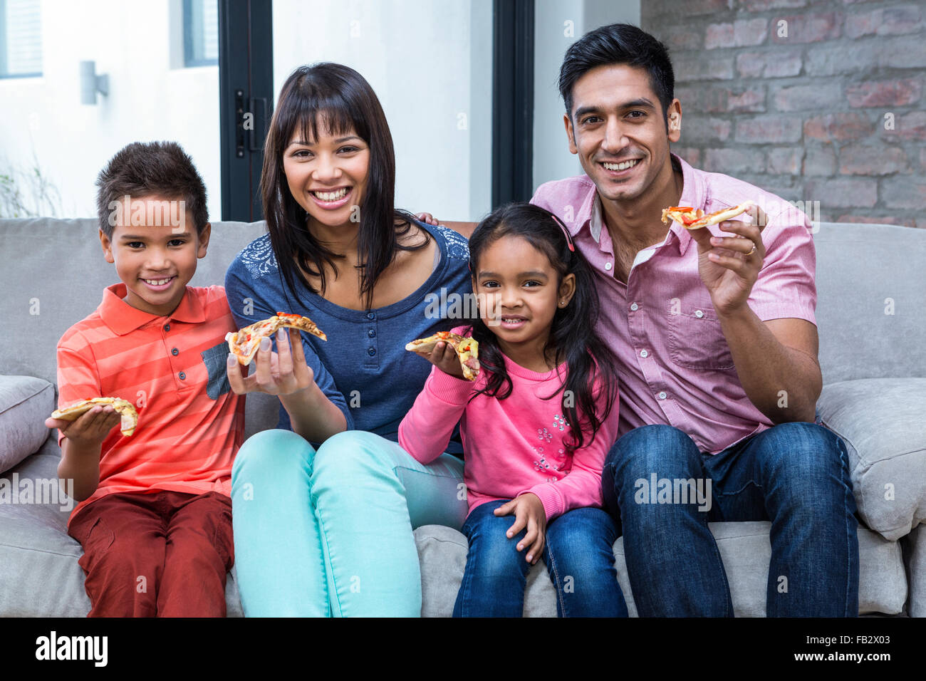 Happy family eating pizza on the sofa Stock Photo - Alamy