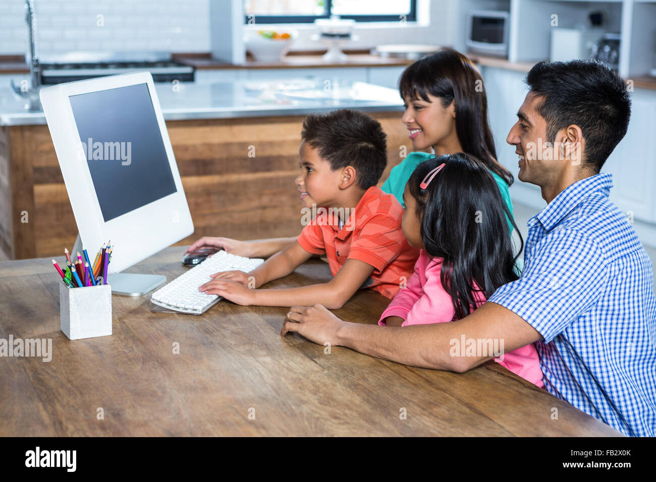 Happy family using computer in kitchen Stock Photo - Alamy