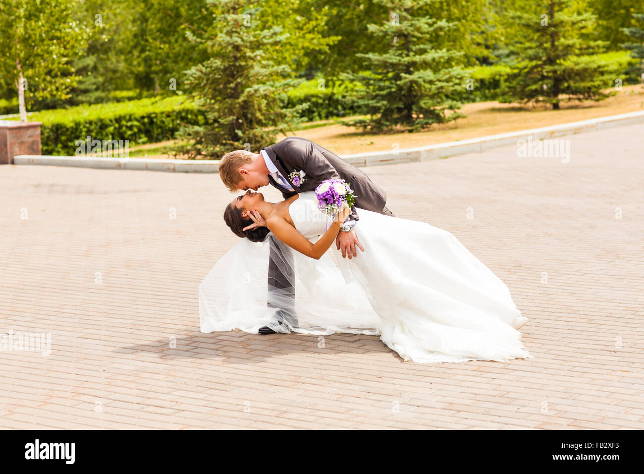 Groom holding bride in dance pose on wedding day Stock Photo - Alamy