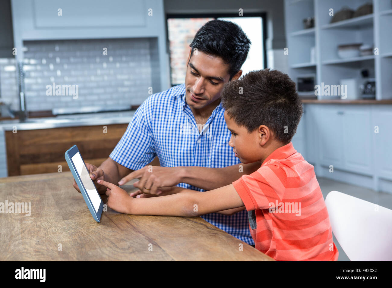 Smiling father using tablet with his son Stock Photo - Alamy