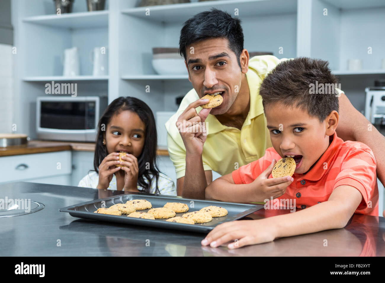Smiling father with his children eating biscuits Stock Photo - Alamy