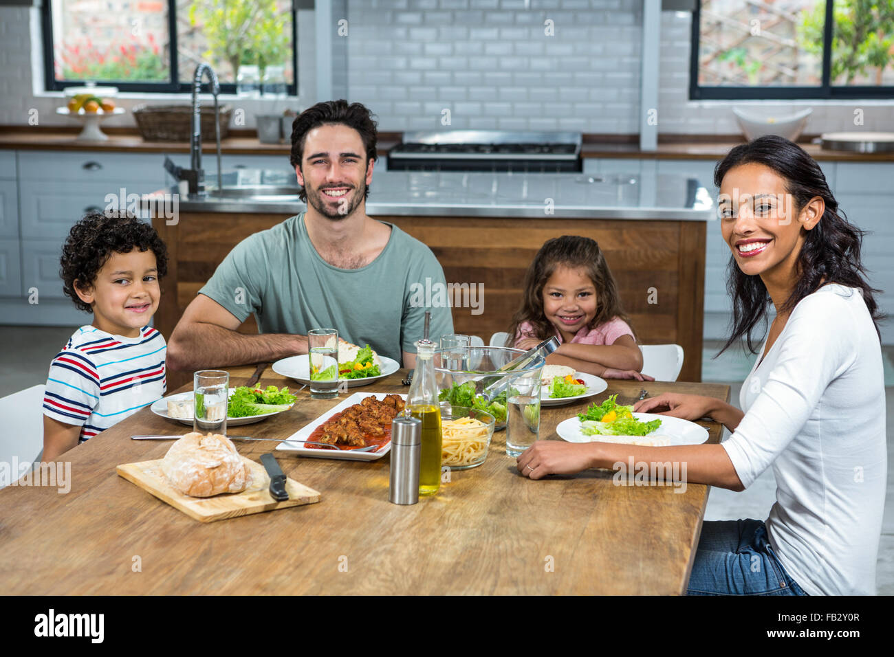 Happy family eating together in the kitchen Stock Photo - Alamy