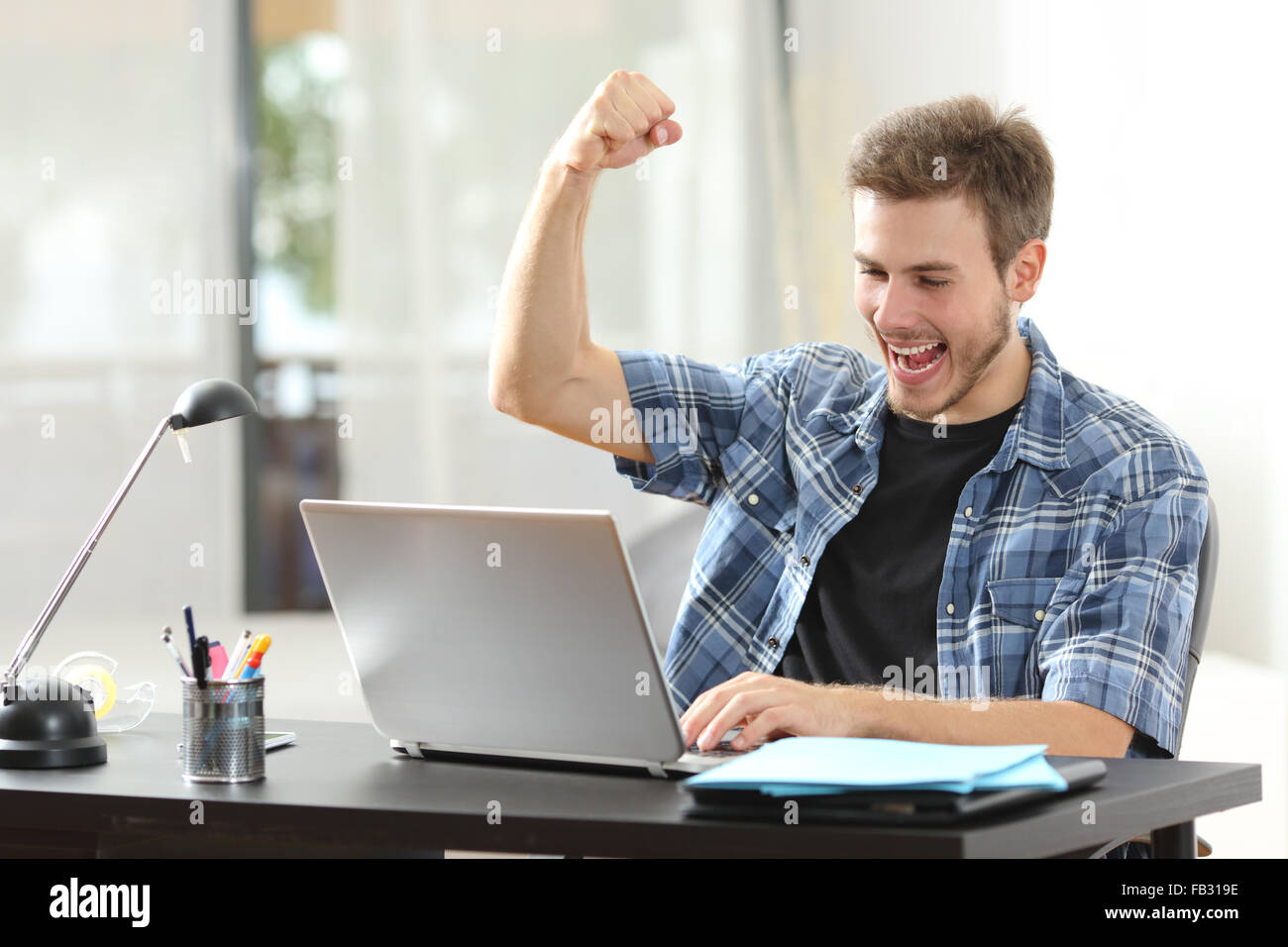 Euphoric winner happy man using a laptop in a desk at home Stock Photo ...