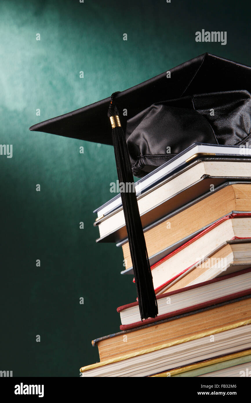 Graduation cap with book in front of black board Stock Photo - Alamy