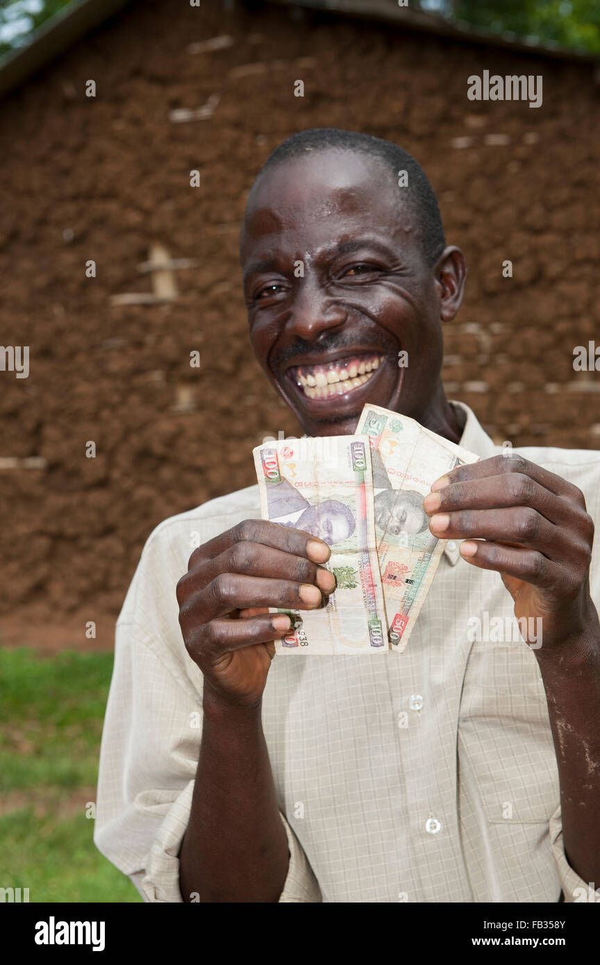 Happy Kenyan farmer holding banknotes earned by selling milk from his ...