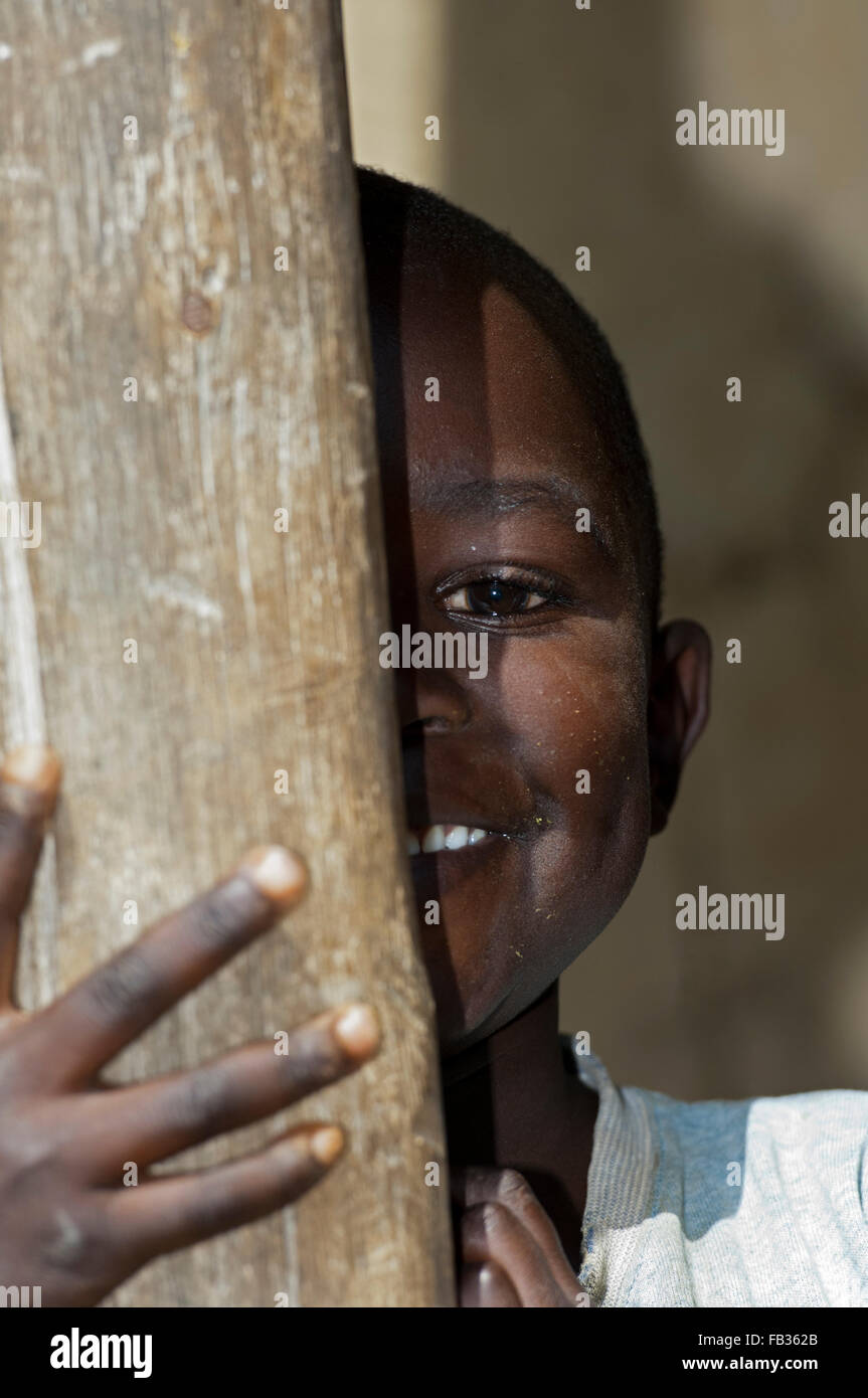 Shy Kenyan child hiding behind a piece of wood. Kenya Stock Photo - Alamy