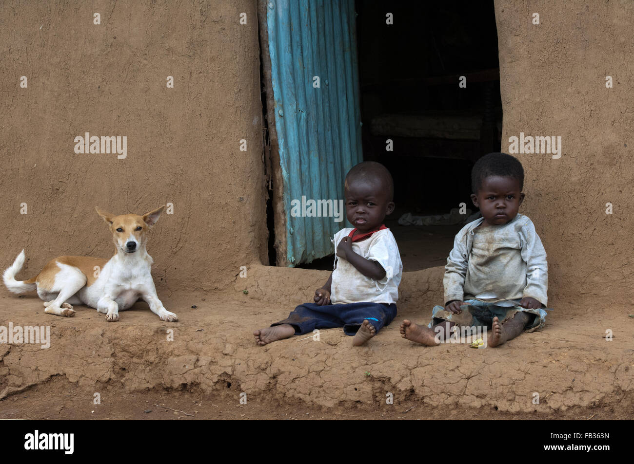 Young undernourished children sitting outside their home in poor ...