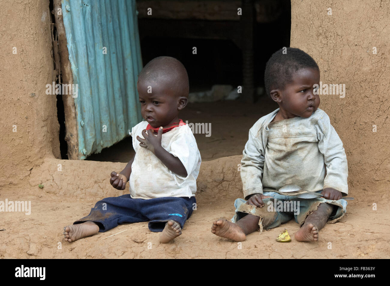 Young undernourished children sitting outside their home in poor ...
