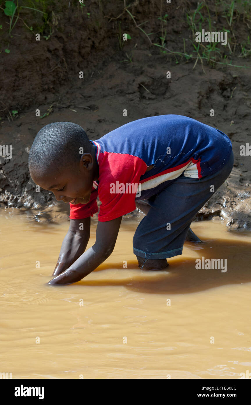 Young child getting water from a muddy river, Kenya Stock Photo - Alamy