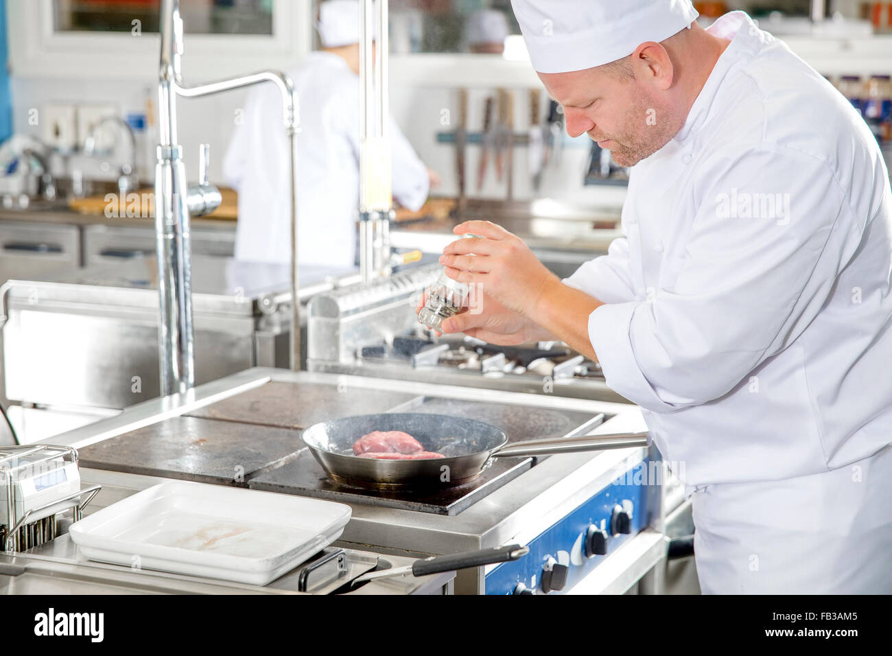 Professional chef adding pepper on steak in the kitchen Stock Photo - Alamy