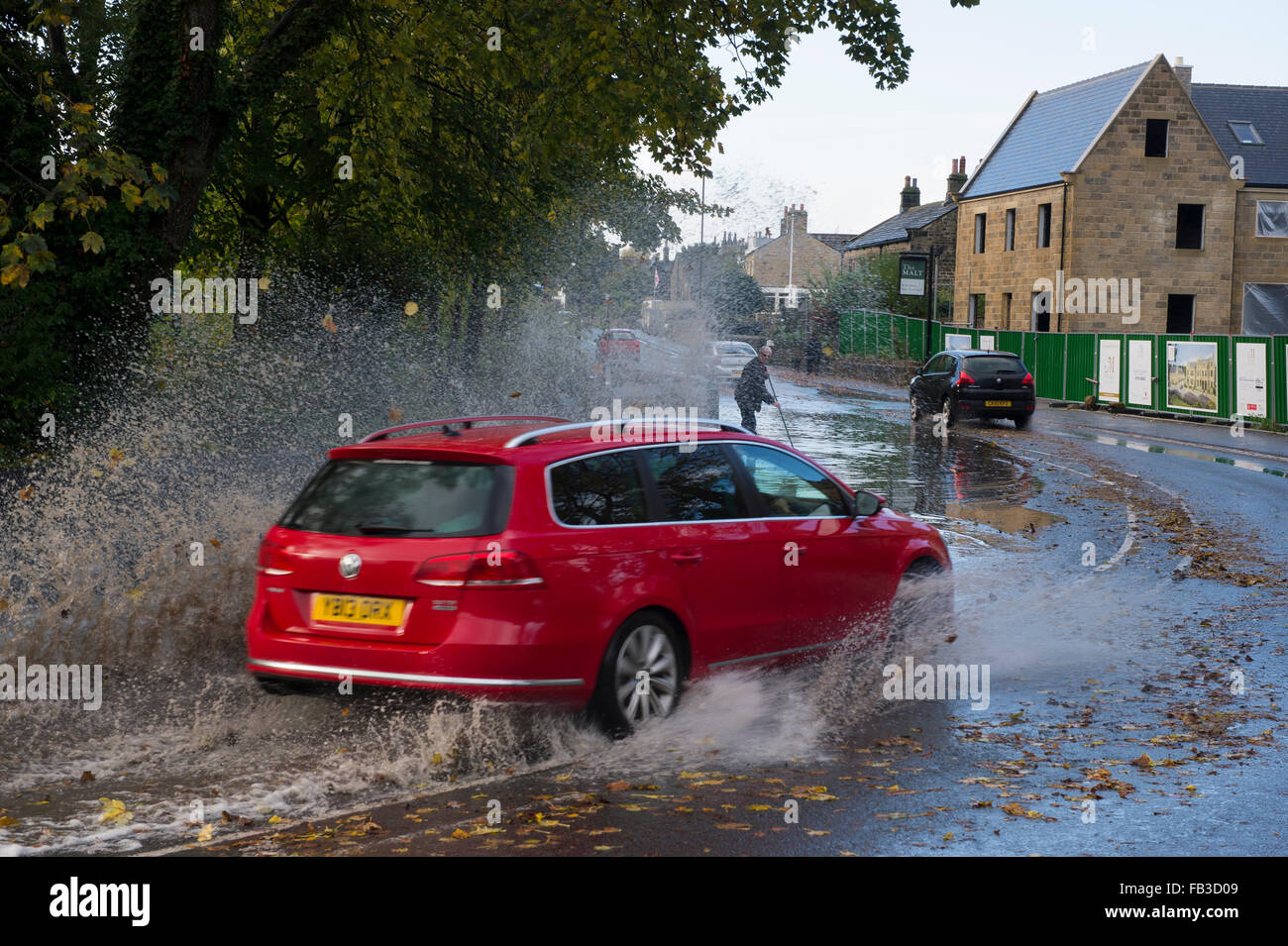 After heavy rainfall, car drives through large puddle on flooded road ...