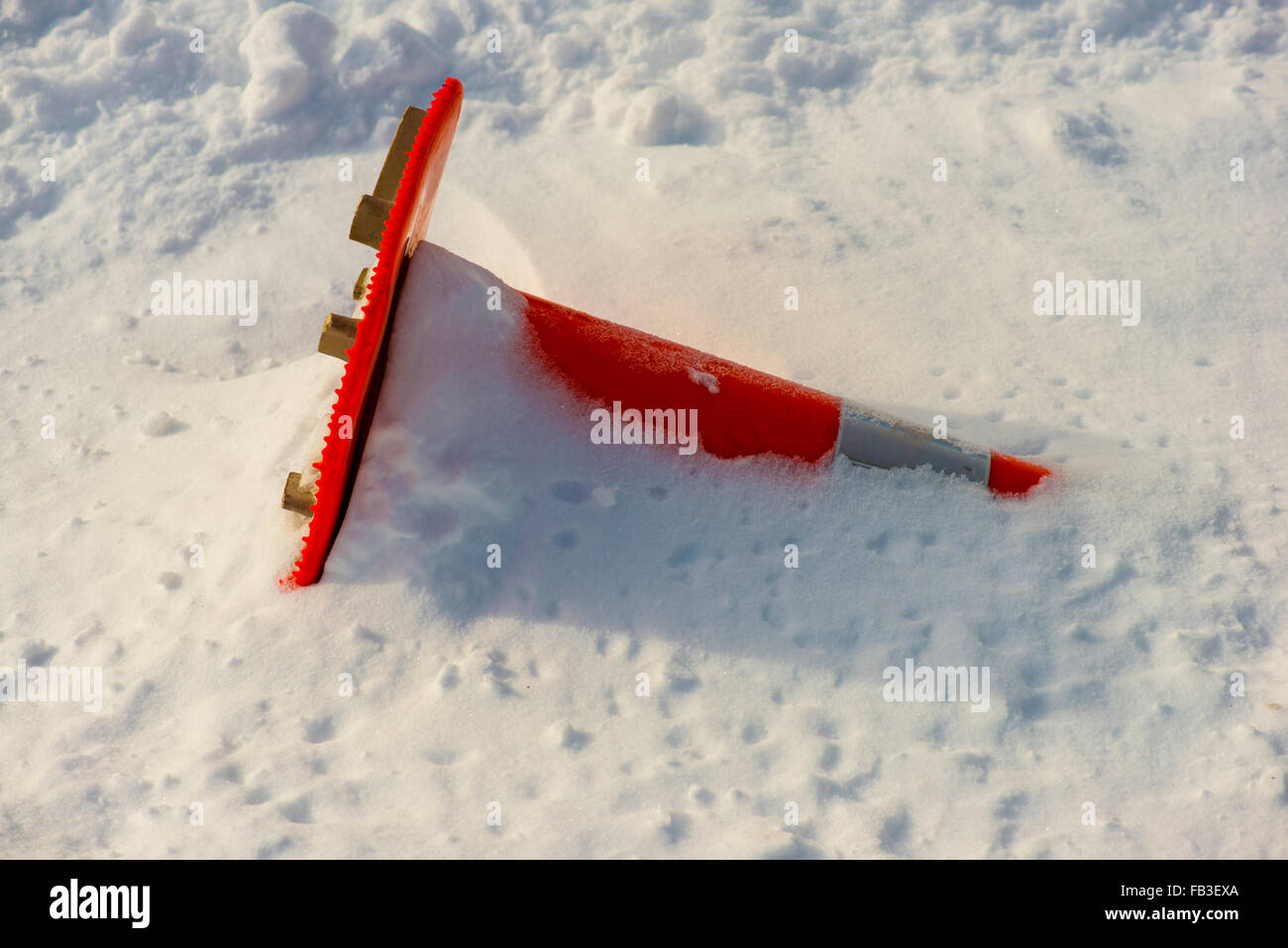 A safety-orange warning cone from construction buried in the snow ...