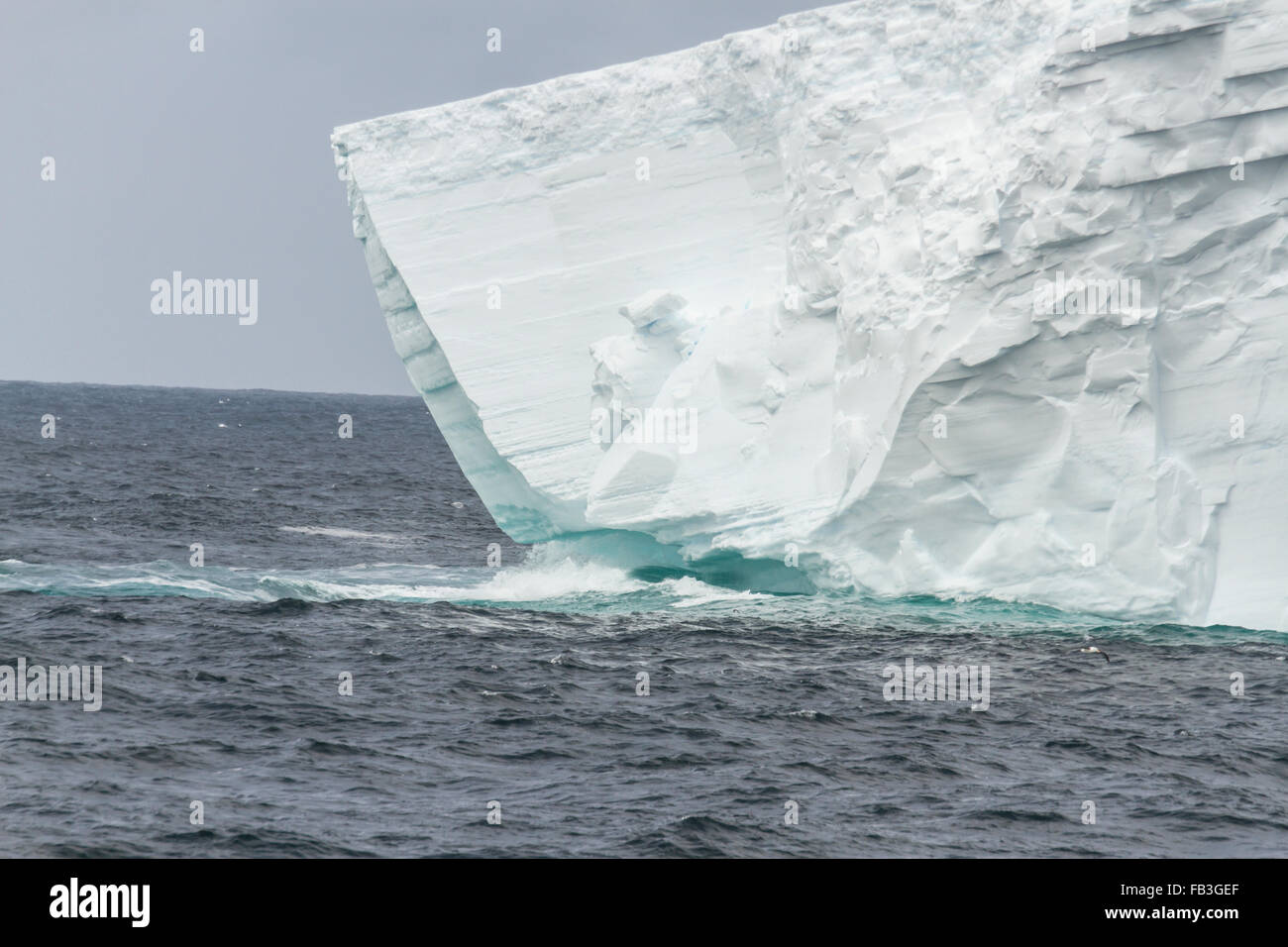 Waves crashing against shelf iceberg floating in seas near Antarctic ...