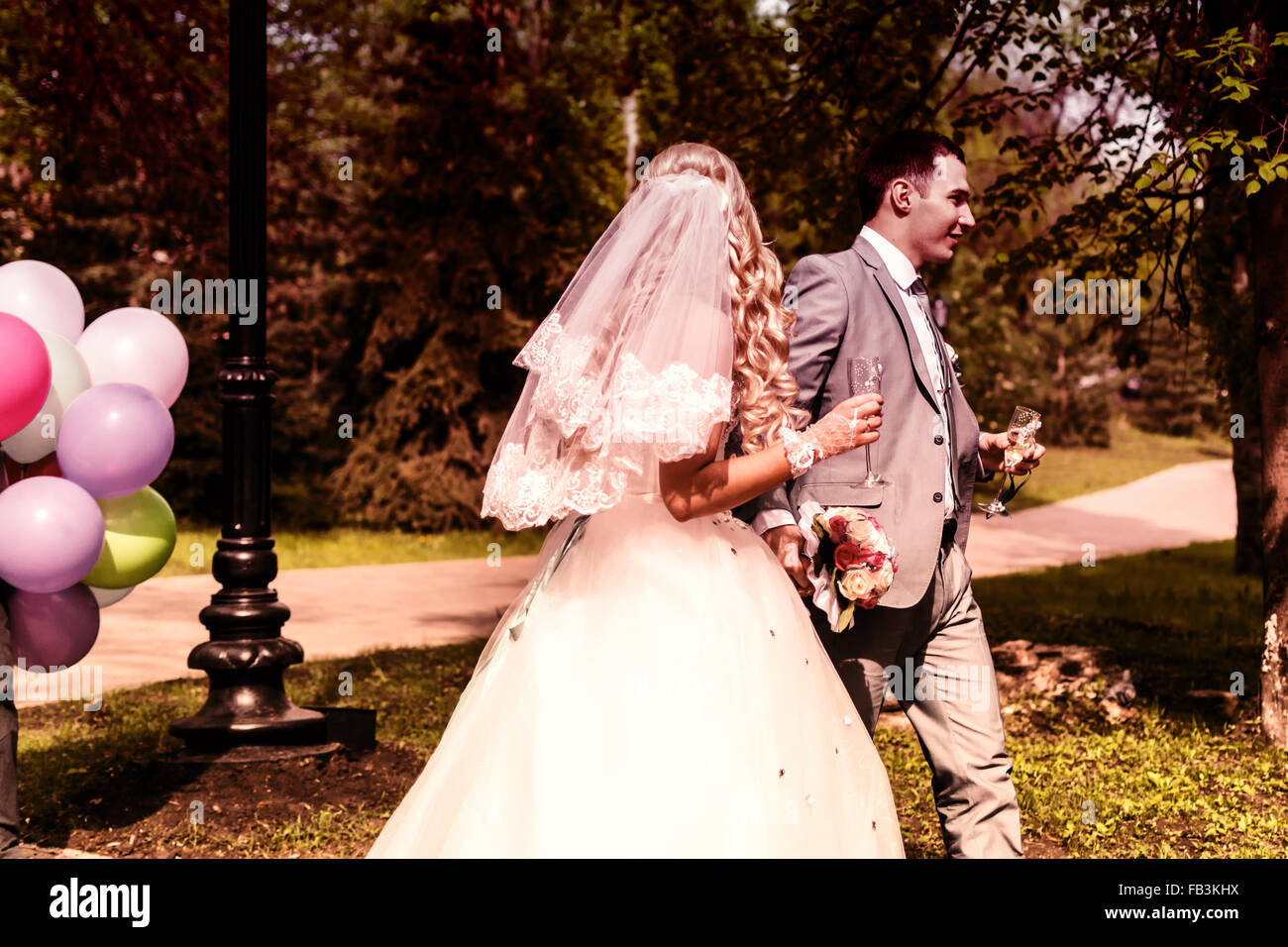 young married couple walk in a park in April as they escape wedding ...