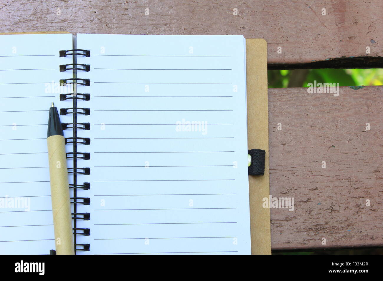 notebook and pen on the brown bench during daytime Stock Photo - Alamy