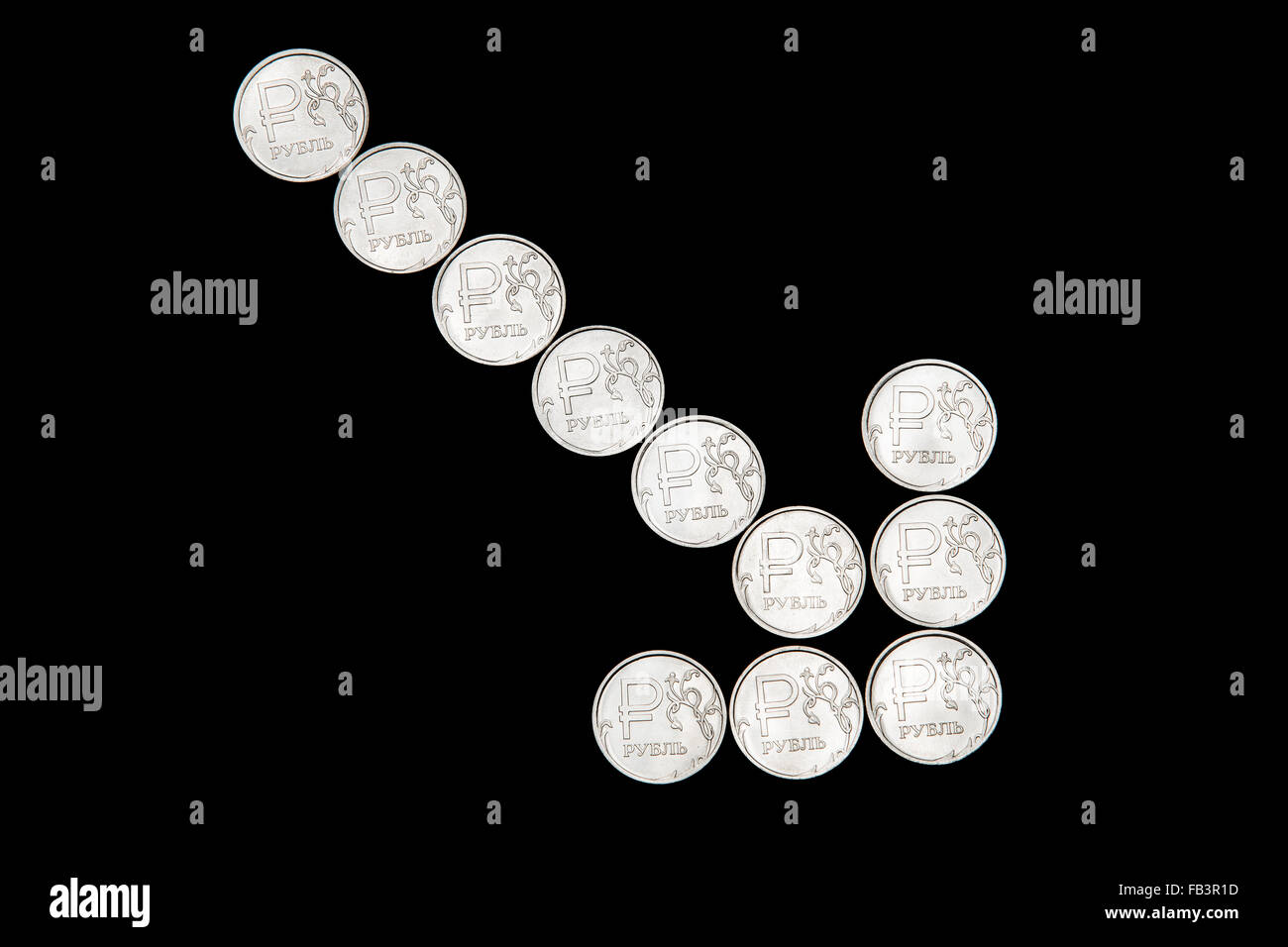 Several metal Russian ruble coins on black background form down arrow ...