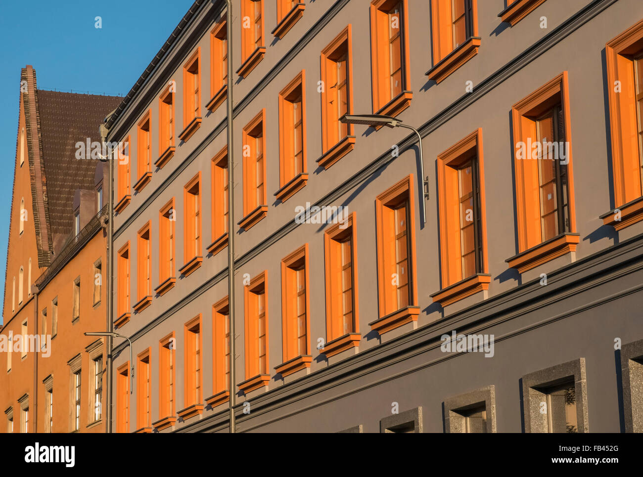 Row of brightly coloured apartments exterior with orange window frames ...
