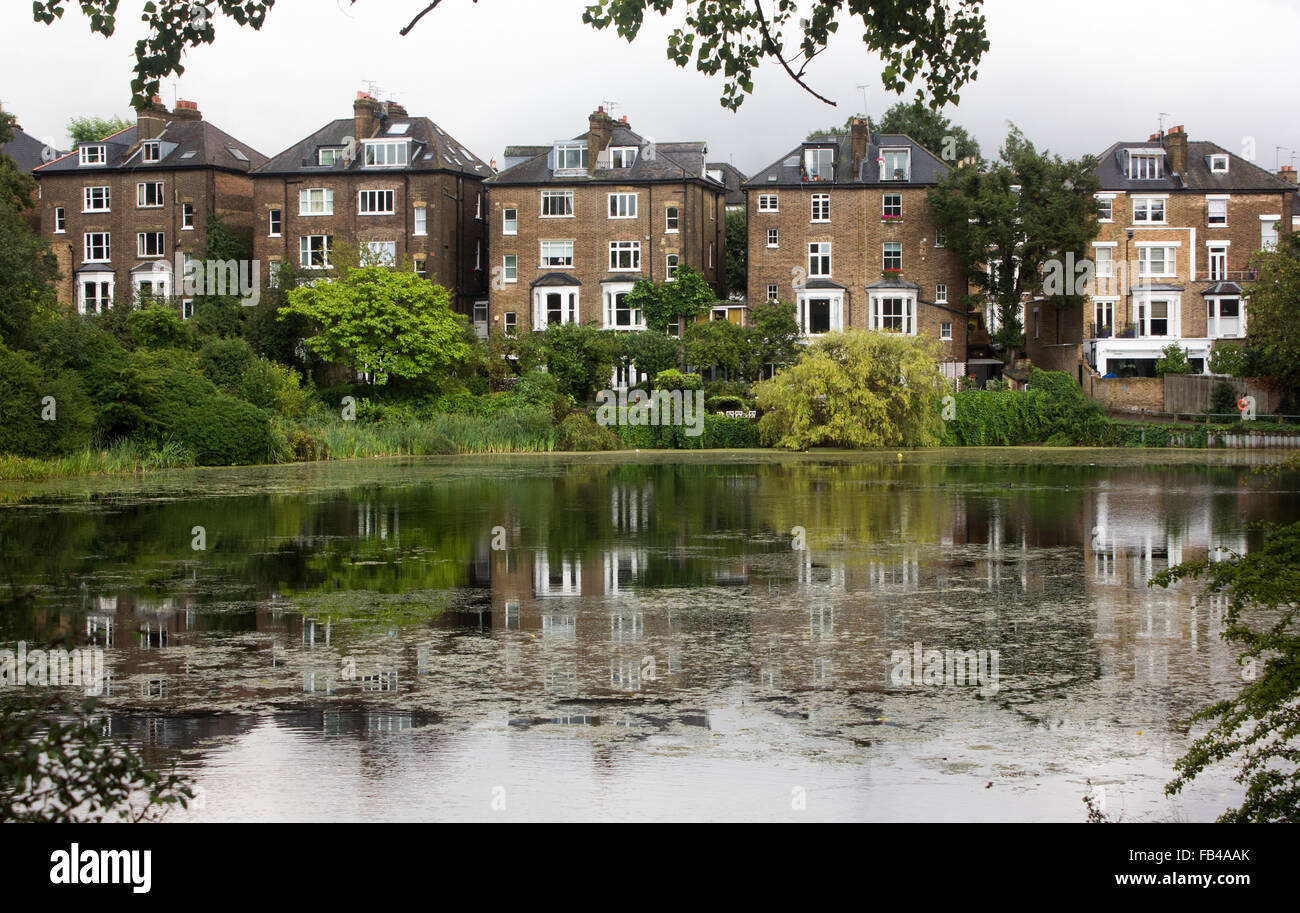 Houses overlooking a lake with a vivid reflection at Hampstead Heath ...