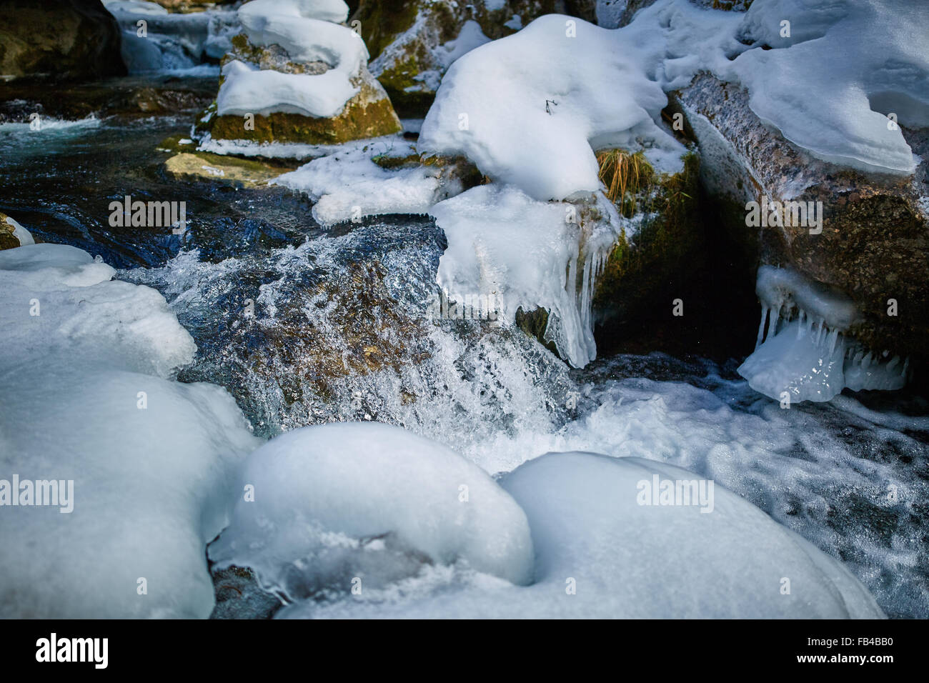 Closeup of a frozen mountain river flowing through icy rocks Stock ...