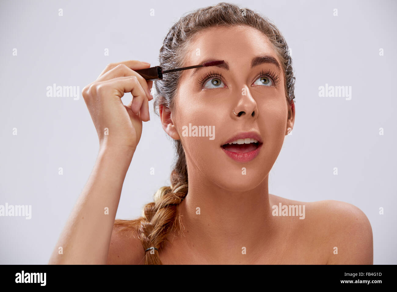 Pretty young woman with a long braid over her bare shoulder applying ...