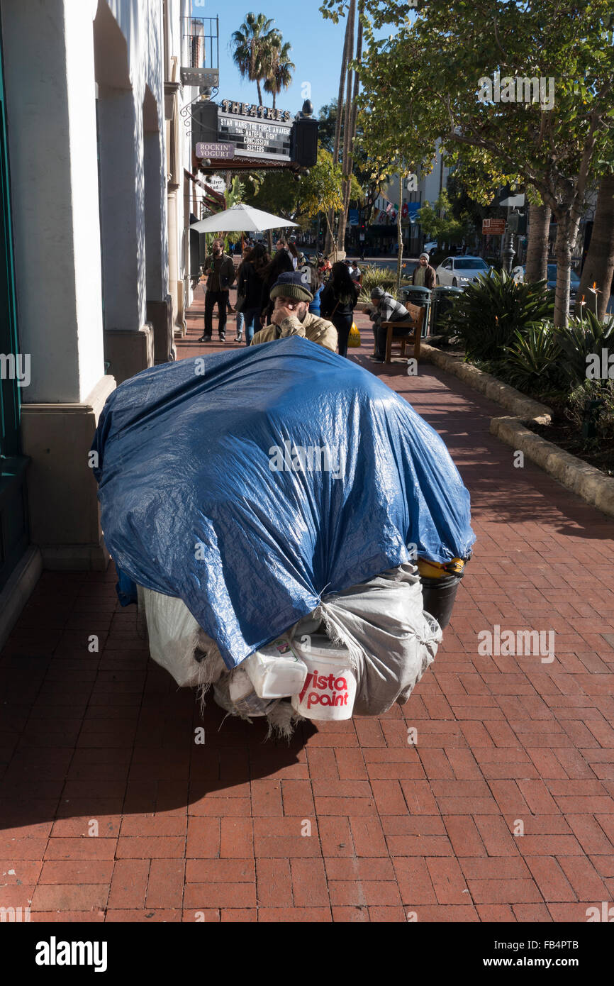 A frontal view of a homeless man wearing a wool cap & tan coat standing ...