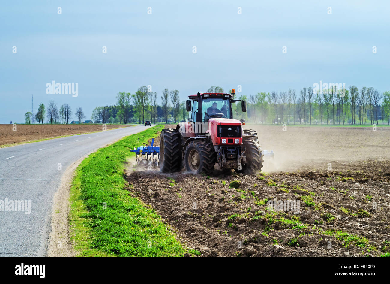 The tractor works at an agricultural field Stock Photo - Alamy