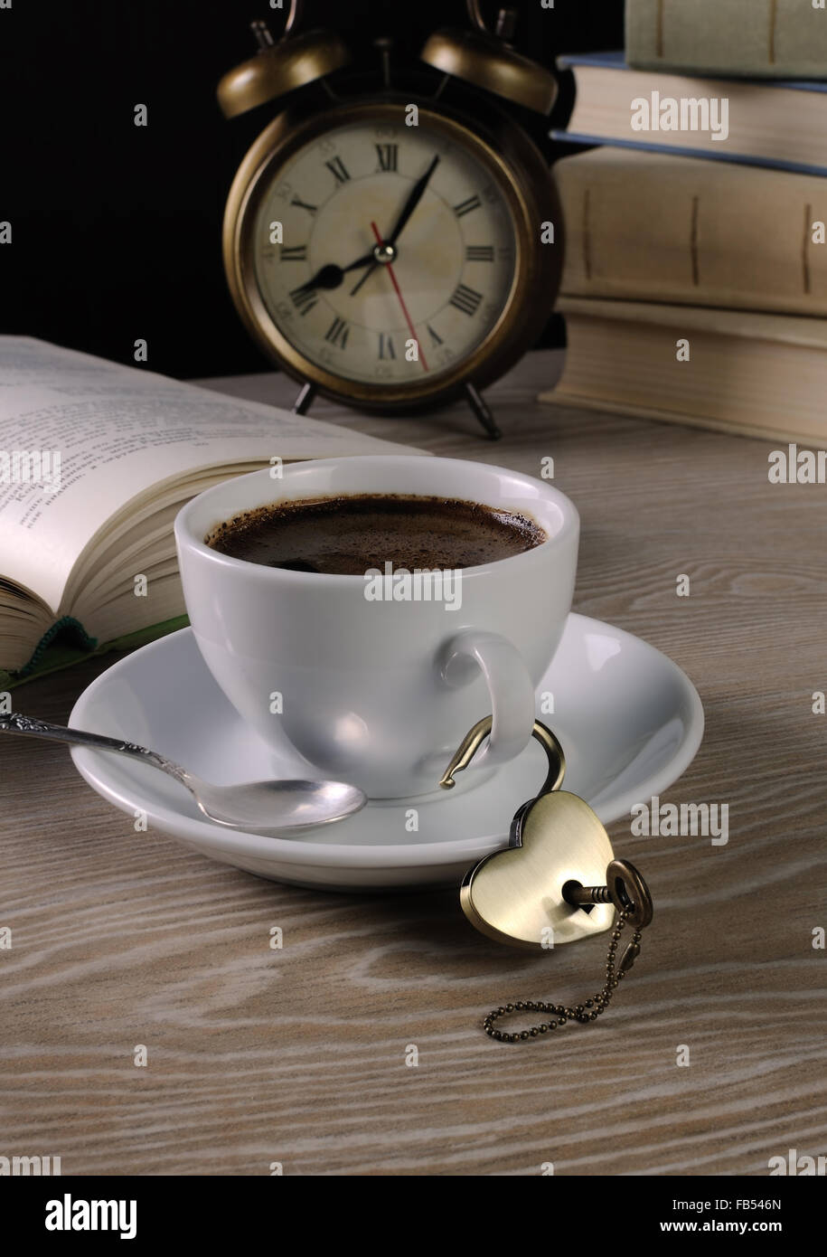Heart shaped lock and key hanging on the handle of a cup of coffee ...