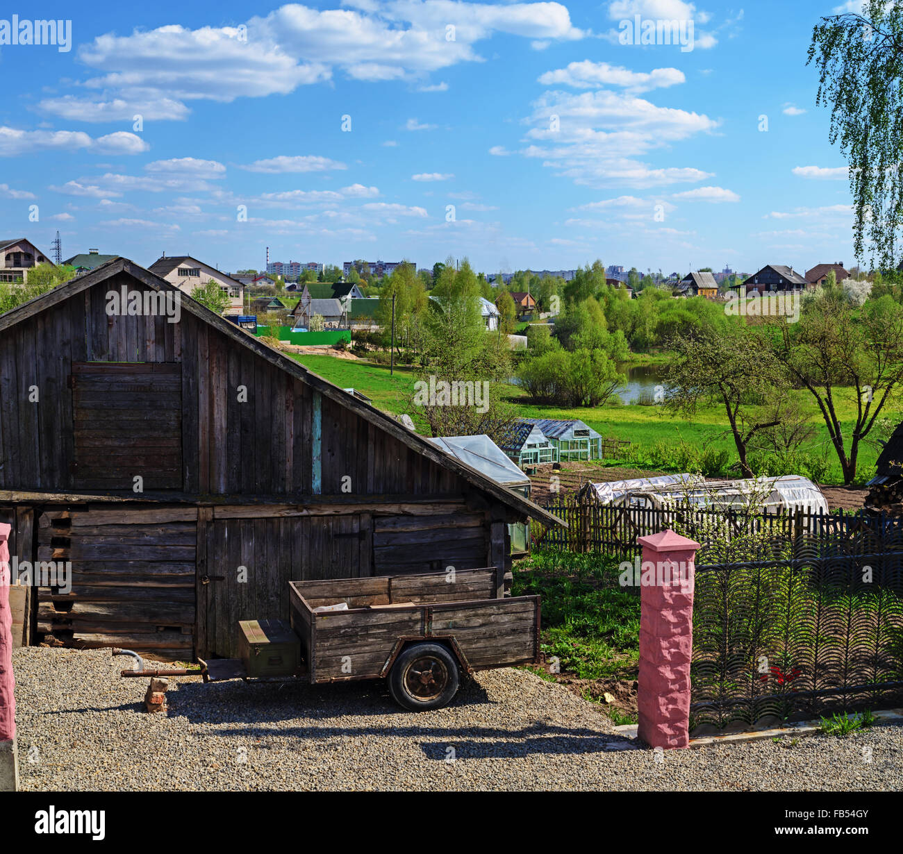 Spring village landscape. Garden and old shed with small tractor ...