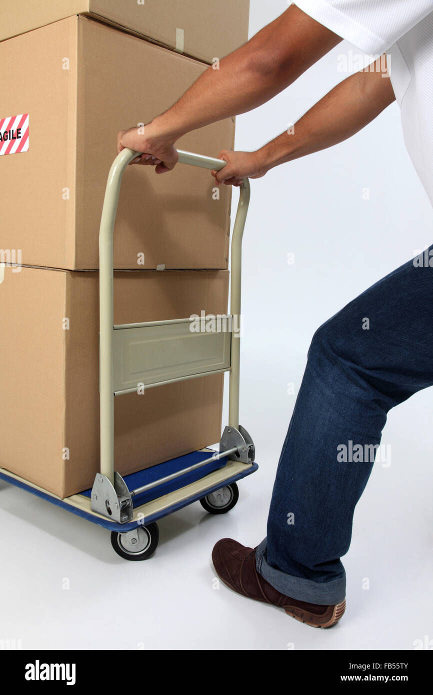 delivery man pushing a trolley with boxes Stock Photo - Alamy