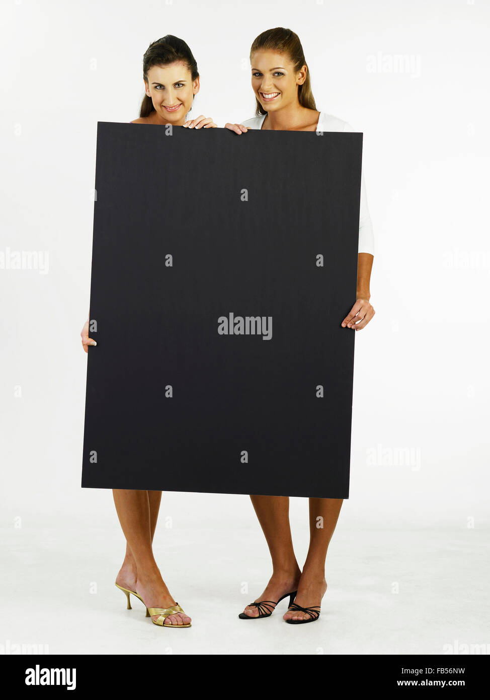 two woman holding a big size card Stock Photo - Alamy