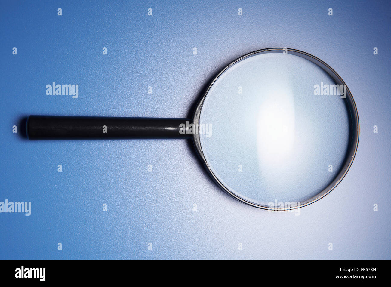 A black magnifying glass with blue background Stock Photo - Alamy