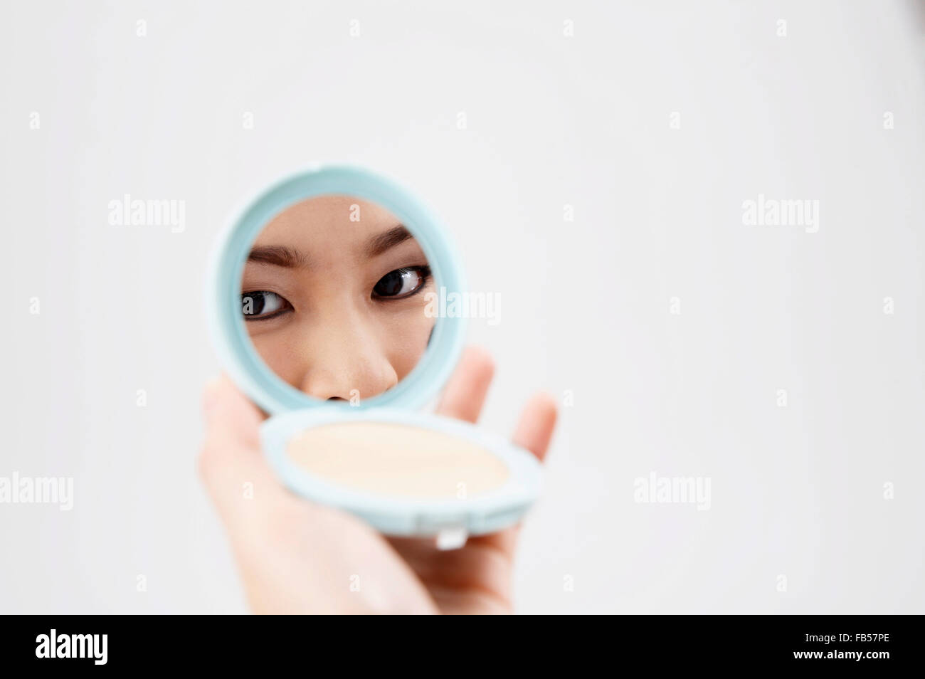 Woman looking in compact mirror Stock Photo - Alamy