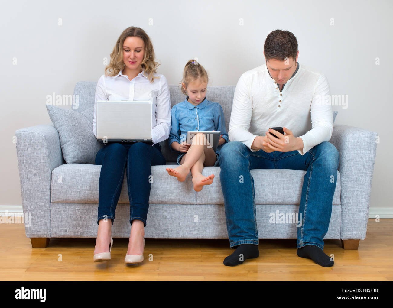 Modern family values. Father, mother and daughter using electronic ...