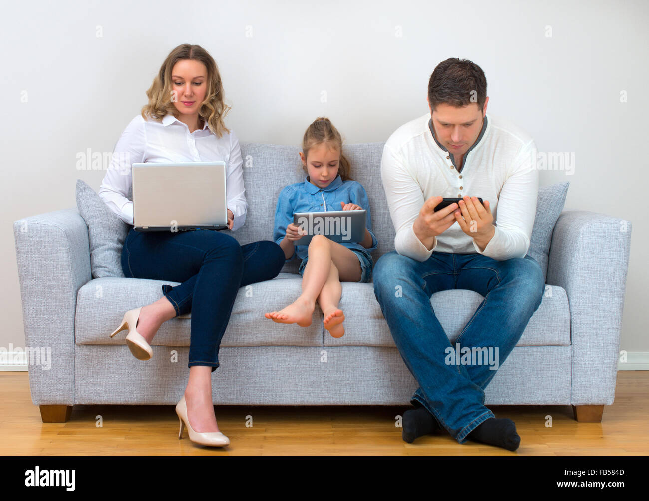 Modern family values. Father, mother and daughter using electronic ...