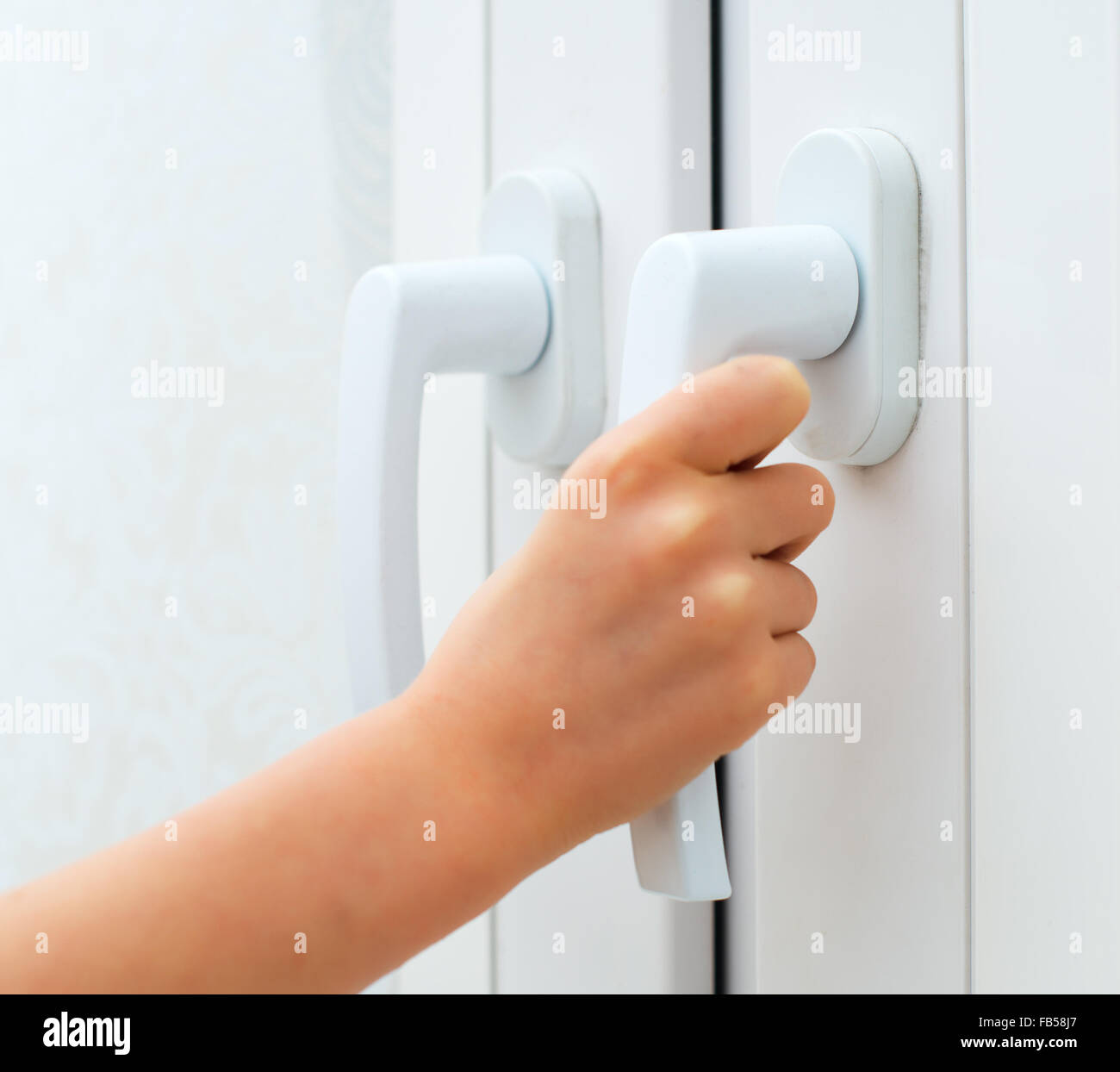Child tries to open window. Dangerous situation at home Stock Photo - Alamy