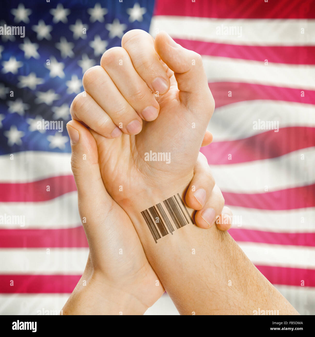 Barcode ID number on wrist of a human and national flag on background ...