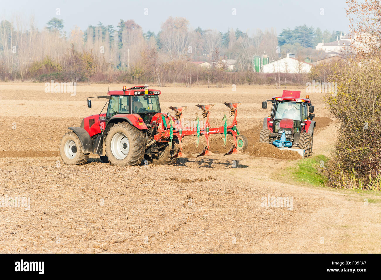 Agricultural labor, Red Tractor plowing a field Stock Photo - Alamy
