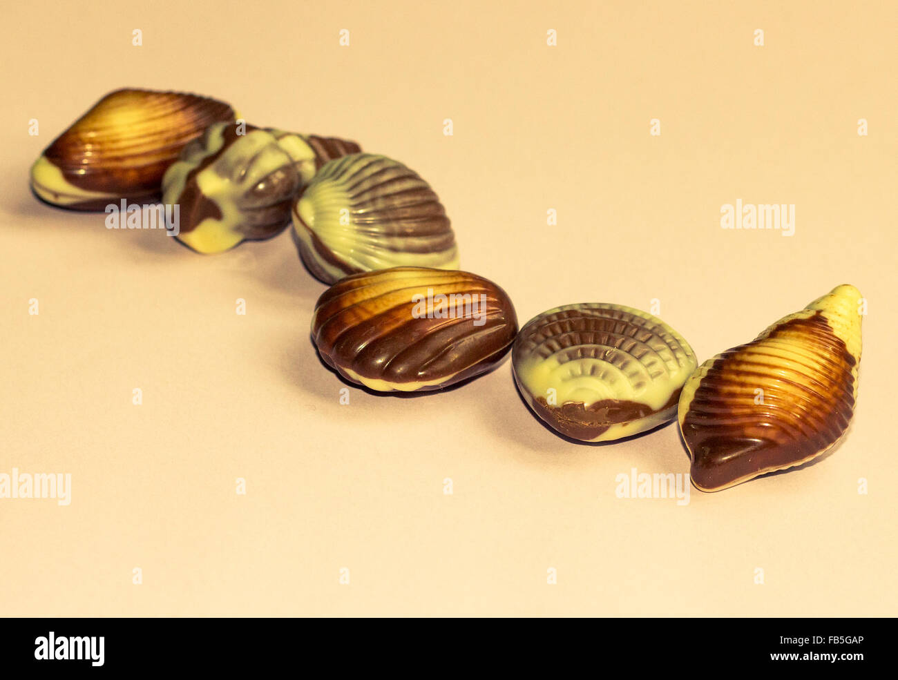 An assortment of Belgian chocolate shells on a yellow/ pale yellow ...
