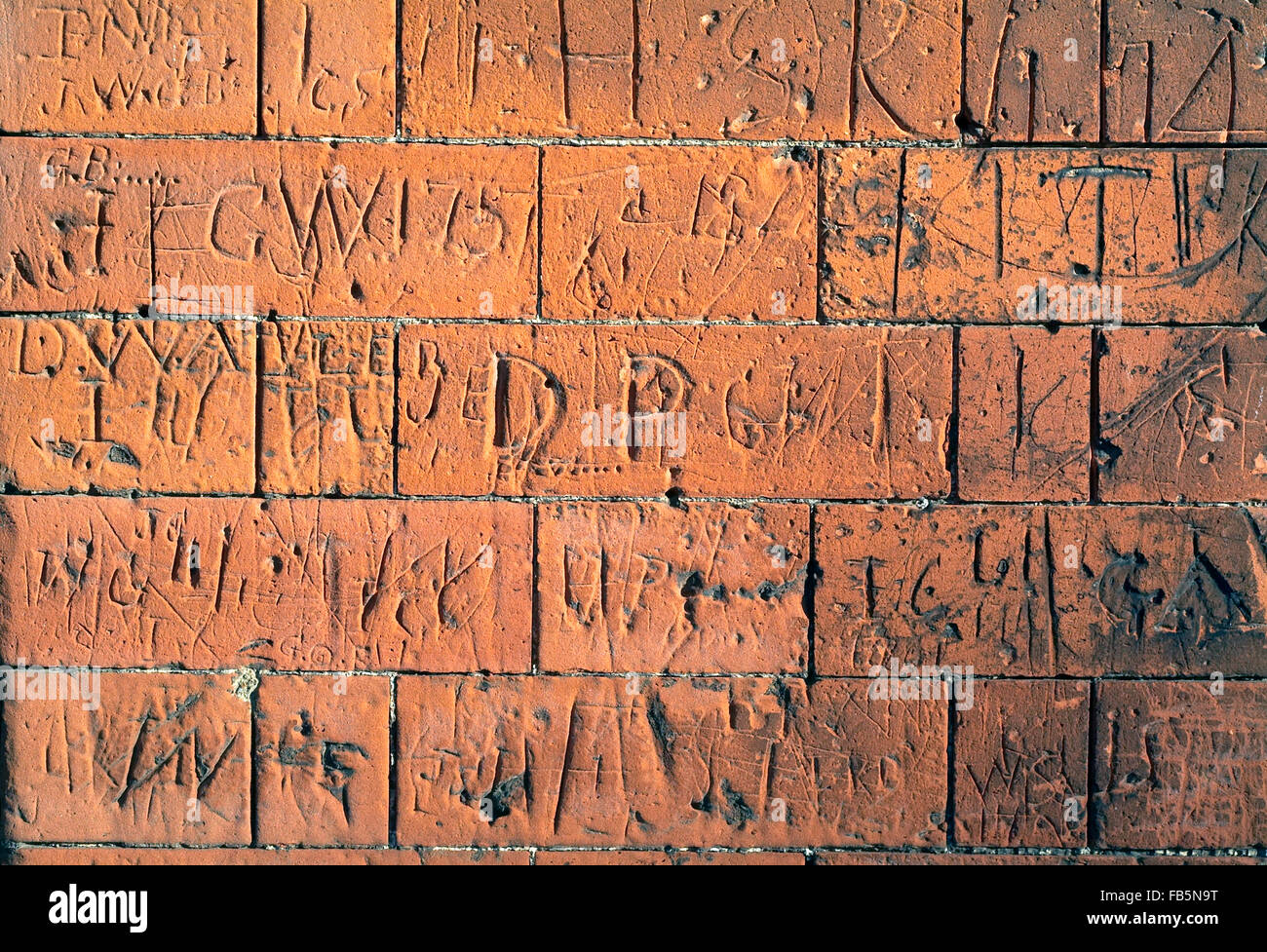 Brick Wall with carved signs and words Stock Photo - Alamy