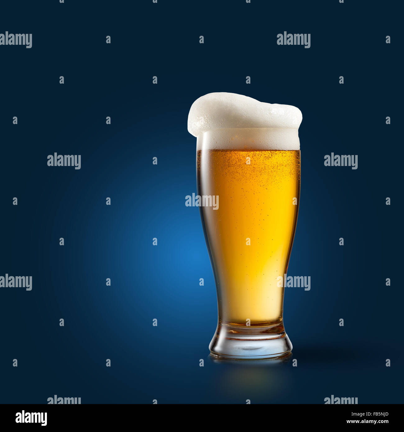 Beer in glass on blue background Stock Photo - Alamy