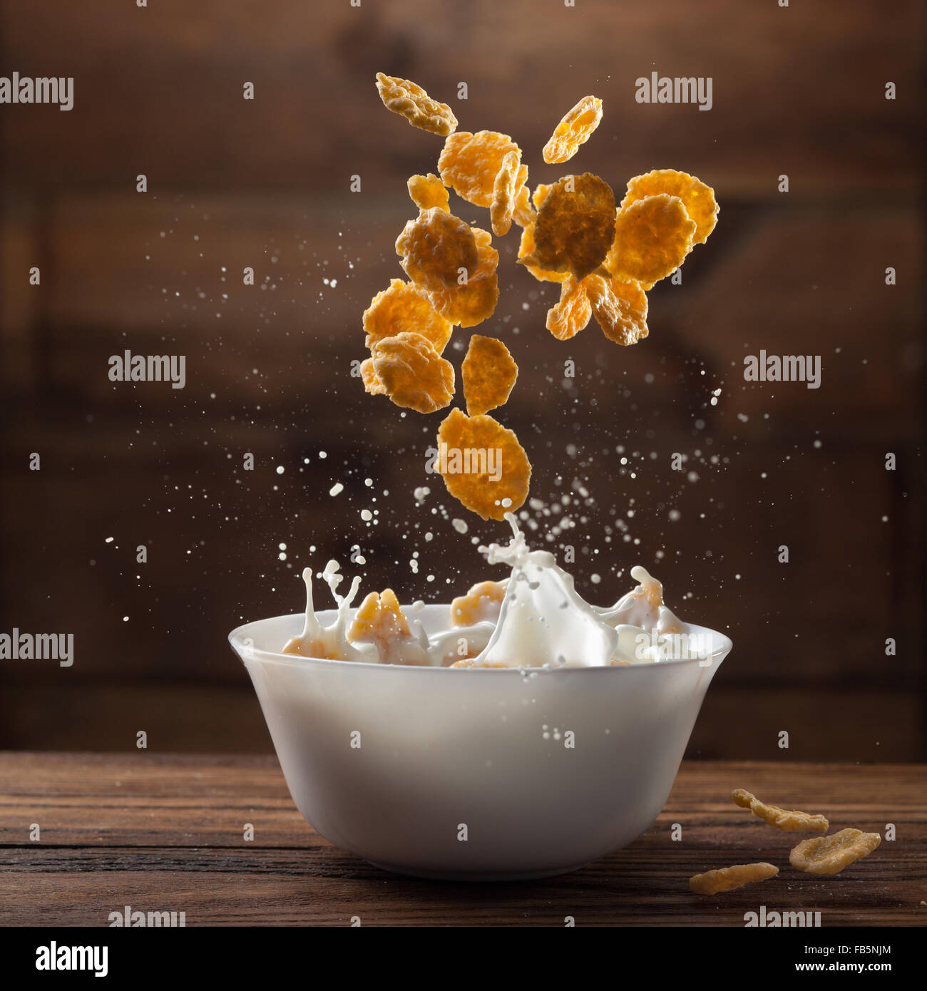 Falling corn flakes with milk splash on wooden background Stock Photo ...