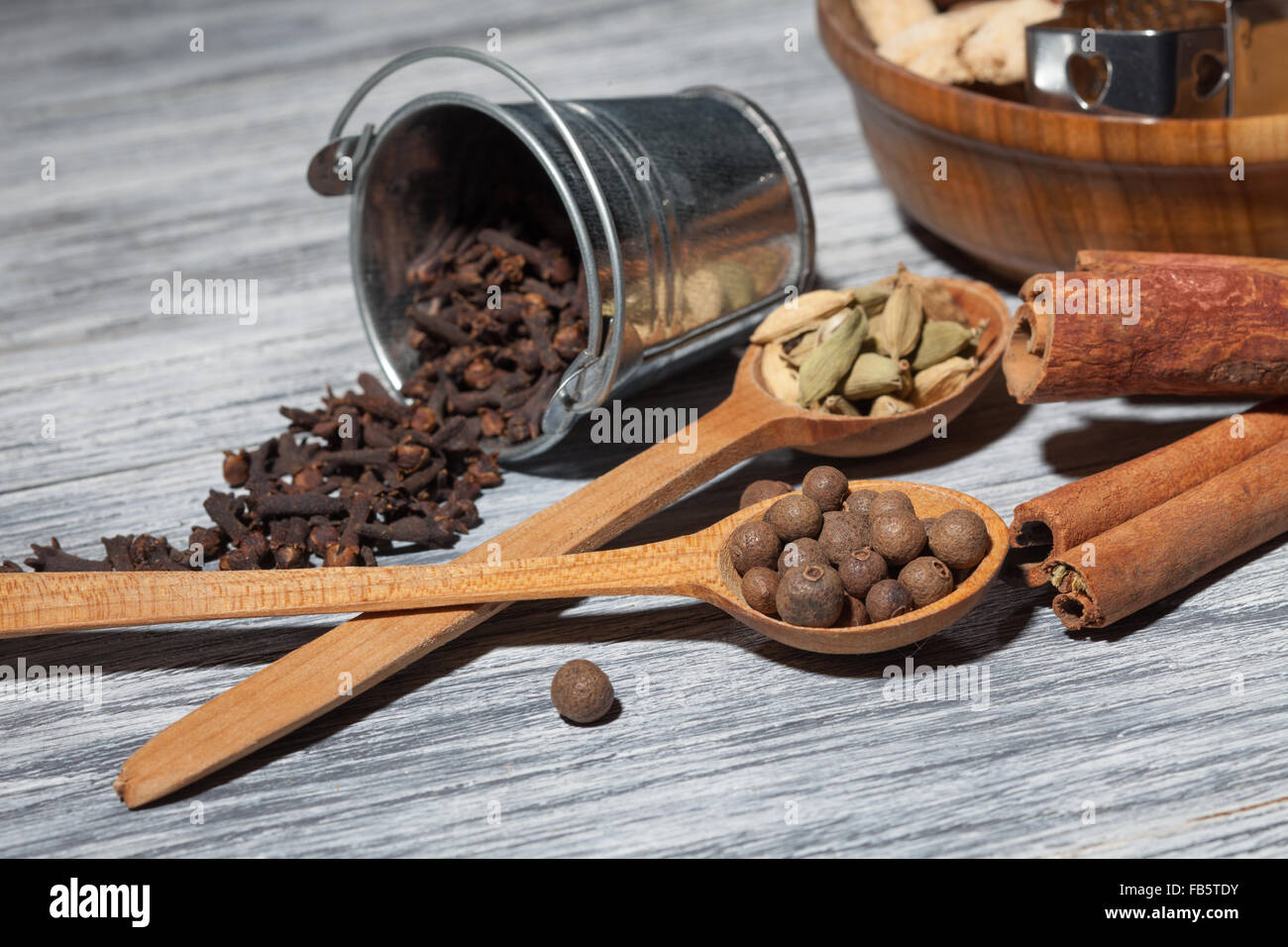 Cardamon, clove and pepper in spoons on wooden background with various ...